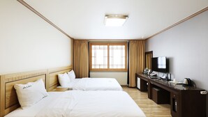 Quarto de hotel com duas camas, uma escrivaninha, uma televisão e uma janela com cortinas.