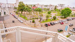 Cruzamento urbano com faixa de pedestres, carros estacionados e uma caminhonete verde.