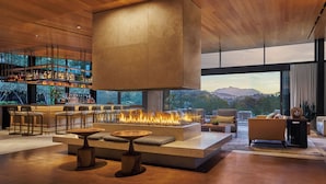 Uma área de bar moderna com uma lareira grande, assentos e vista para o exterior.