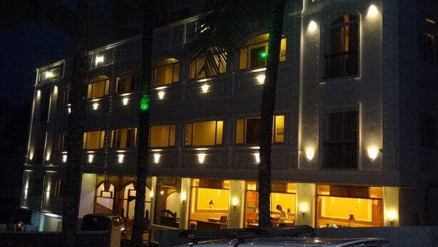 Um hotel com vários andares, janelas iluminadas e um letreiro sobre a entrada.