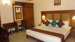 Quarto de hotel com uma cama grande, uma escrivaninha, uma cadeira e um guarda-roupa.