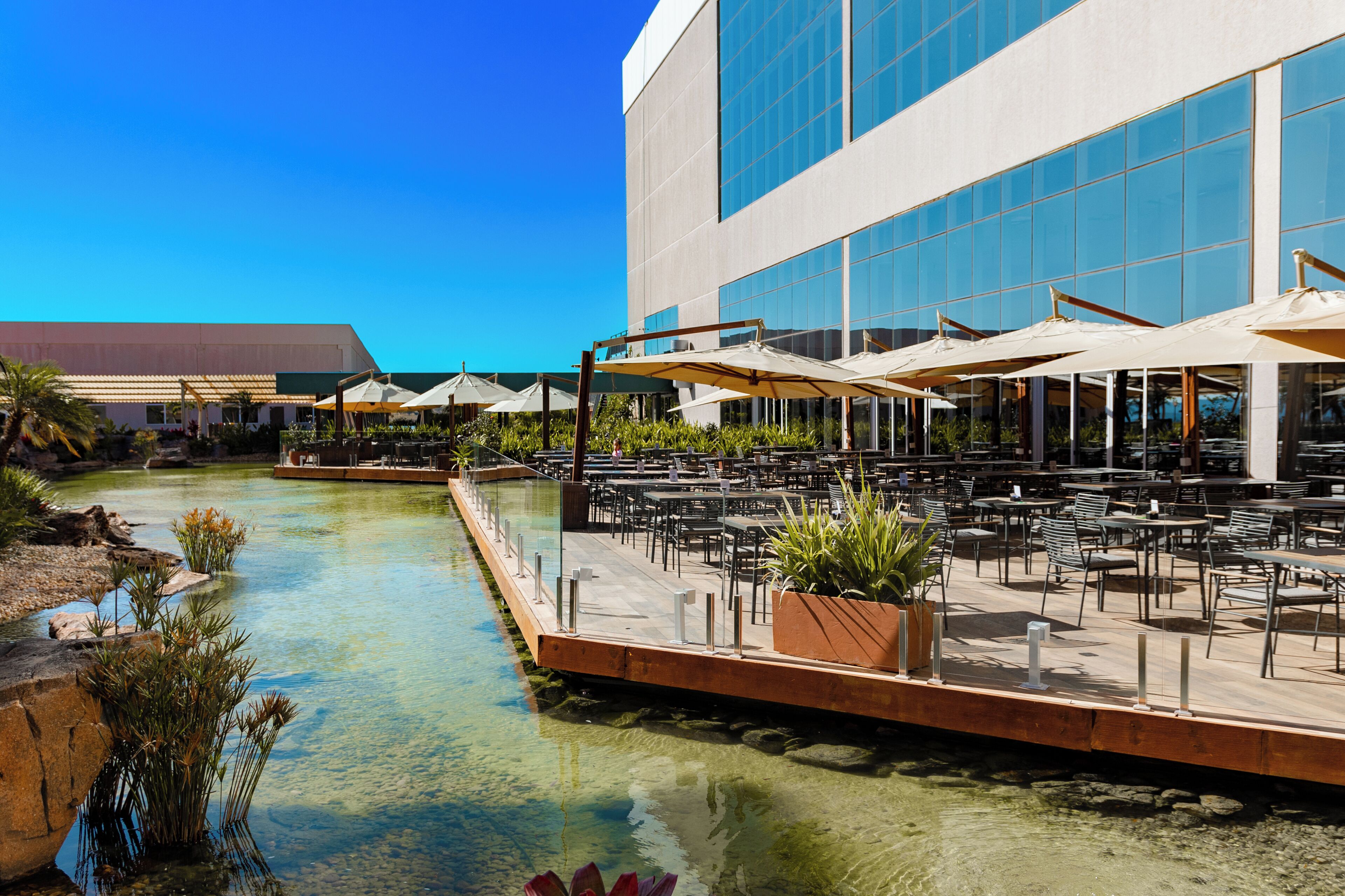 Área da piscina com mobiliário de exterior e um edifício moderno ao fundo.