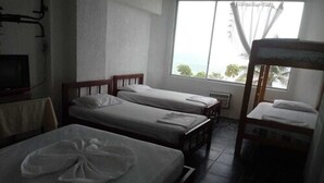 Quarto com duas camas de solteiro, uma beliche e uma televisão, além de janela com vista.