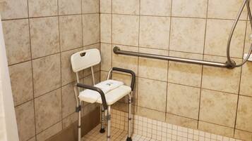 Um banheiro com piso de azulejos brancos, vaso sanitário branco e barra de apoio na parede.