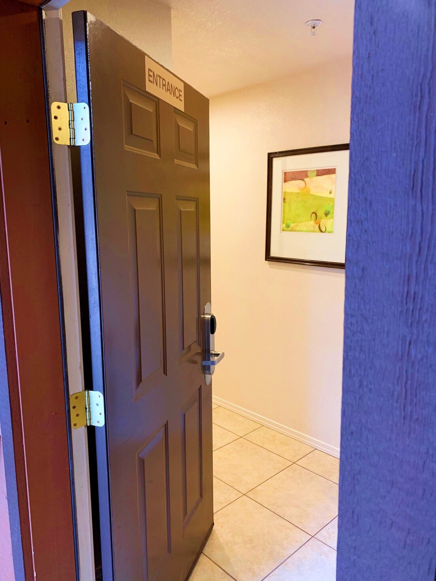 Uma porta fechada com uma placa que diz 'ENTRADA' e uma imagem na parede.