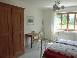 Quarto com uma cama, escrivaninha e guarda-roupa.