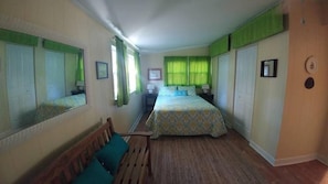 Um quarto com uma cama, um banco e um guarda-roupa.