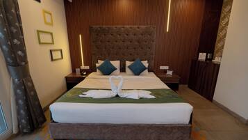 Quarto de hotel com uma cama grande, duas mesas de cabeceira, um painel de cabeceira de madeira e um detalhe decorativo na parede.