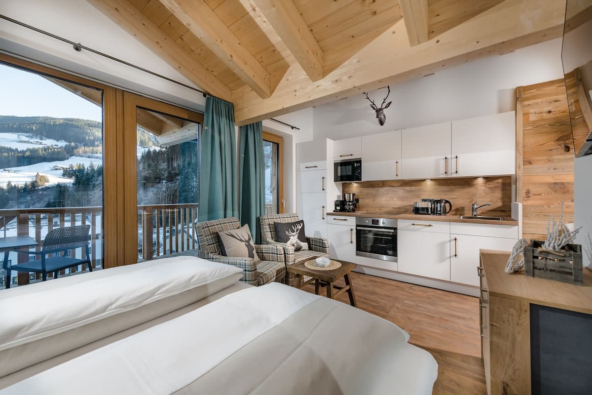 Quarto moderno com uma janela grande, um espaço de estar aconchegante, uma kitchenette e teto de madeira.