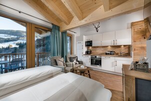 Quarto moderno com uma janela grande, um espaço de estar aconchegante, uma kitchenette e teto de madeira.