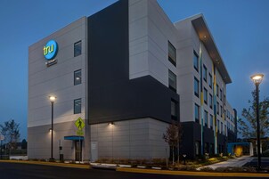 Um edifício de hotel moderno com um letreiro chamativo 'tru by Hilton', uma porta de saída de incêndio e uma placa de faixa de pedestres.