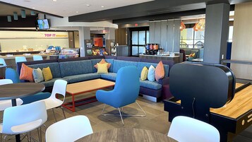 Uma área de estar moderna com um sofá azul, cadeiras brancas e uma mesa de madeira.