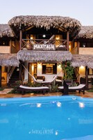 Área da piscina com espreguiçadeiras e uma placa com a inscrição "MAXITALIA".