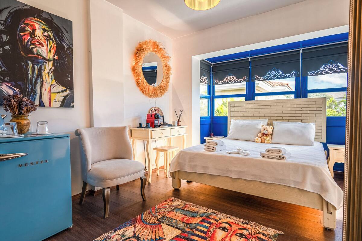 Quarto com cama, escrivaninha, cadeira, cômoda e pintura na parede.