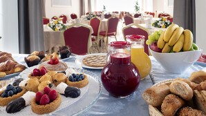 Um buffet de café da manhã com pães, frutas e bebidas.