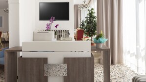 Uma sala de estar moderna com um móvel branco para entretenimento, uma televisão montada na parede e uma área de jantar com uma cadeira vermelha.