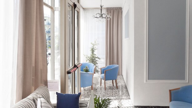 Uma sala de estar moderna com sofá, poltronas, um candelabro e vista através de amplas janelas.