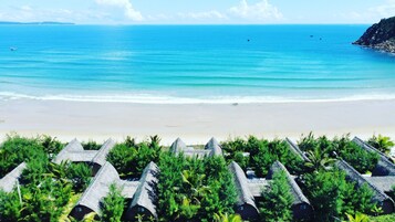 Praia particular, areia branca, espreguiçadeiras, guarda-sóis 