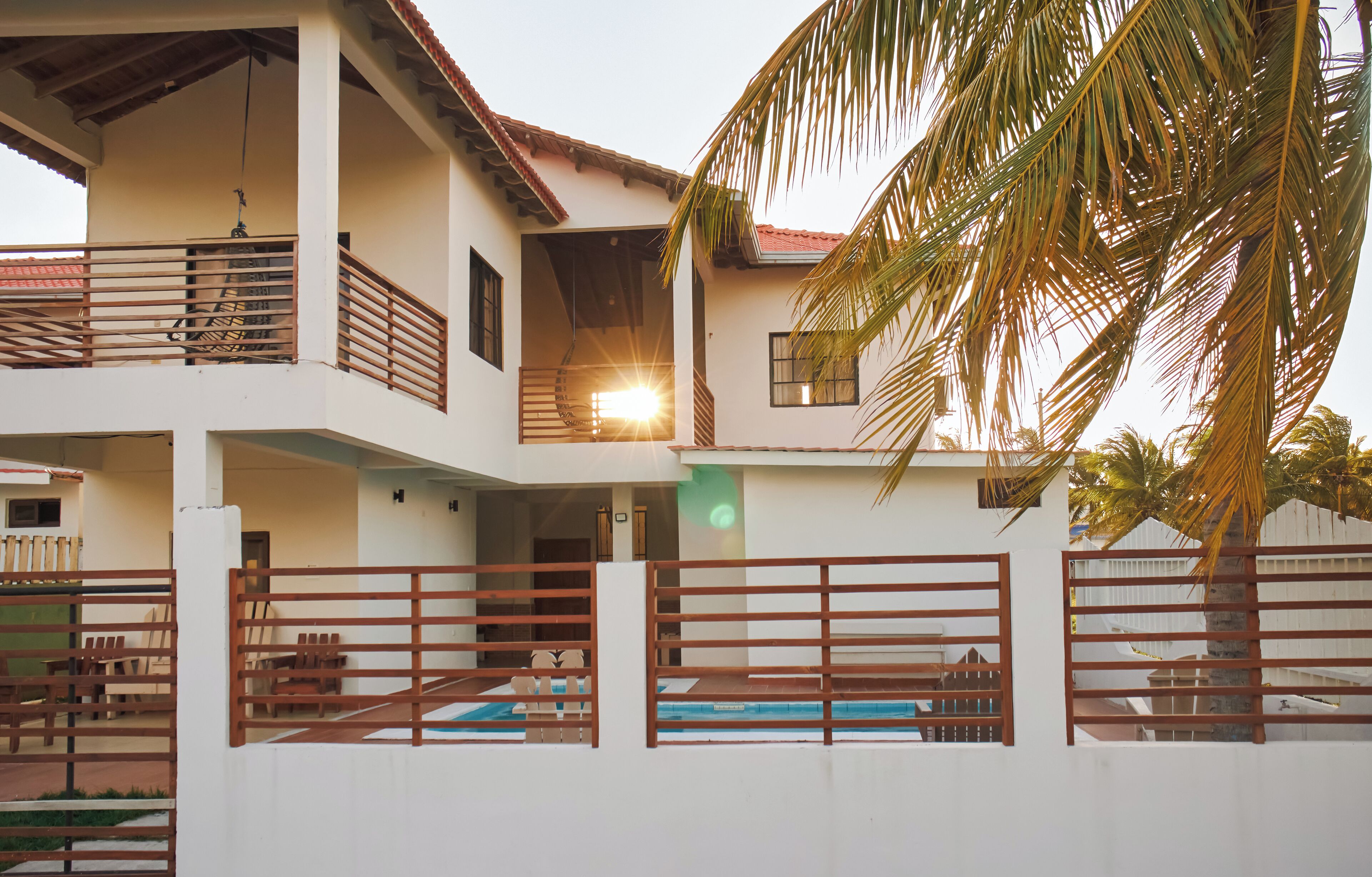 Uma casa de dois andares com varanda, piscina e portão.
