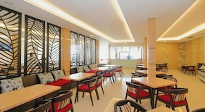 Restaurante moderno com diversas áreas de estar, incluindo cabines e mesas, e cozinha visível ao fundo.
