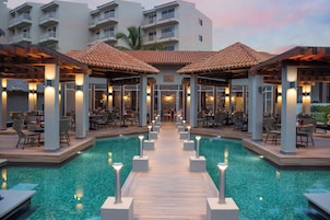 Uma área à beira da piscina com deck de madeira, espreguiçadeiras e um restaurante chamado "The Grill".