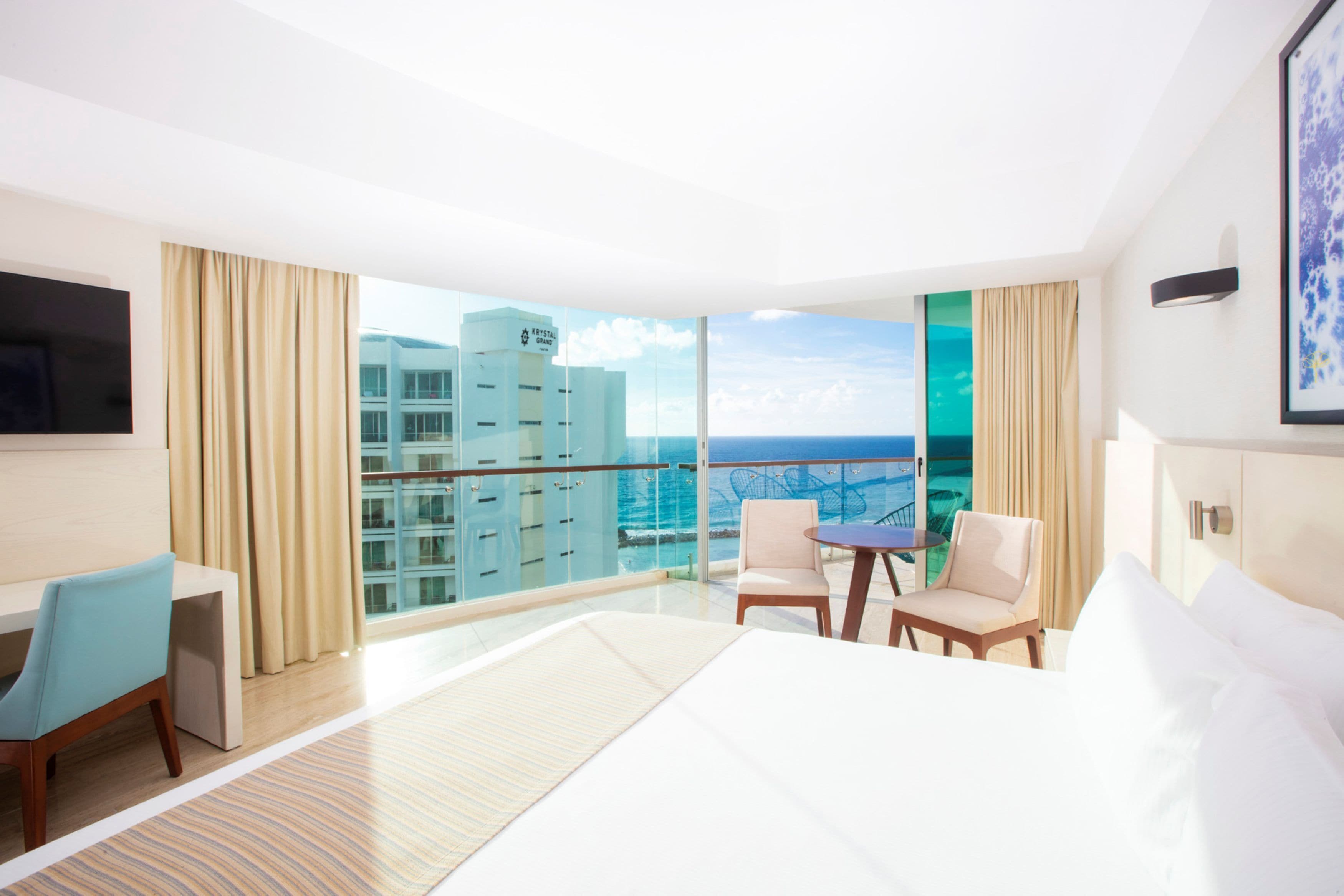 Quarto de hotel moderno com uma varanda grande, uma escrivaninha, uma cadeira e uma cama.