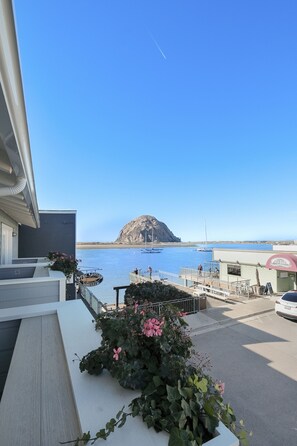 Uma varanda com vista para o mar, um edifício com um letreiro e um carro estacionado.
