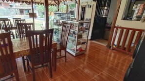 Um restaurante com cadeiras de madeira e uma vitrine de vidro.