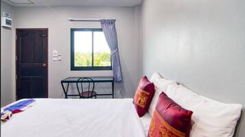 Quarto de hotel com uma cama, uma mesa e uma janela com cortinas.