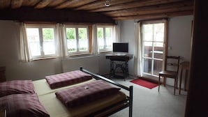 Quarto com duas camas, uma mesa com computador e uma cadeira.