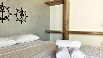 Quarto de hotel com uma cama, almofadas, cabeceira de madeira e espelho fixado na parede.