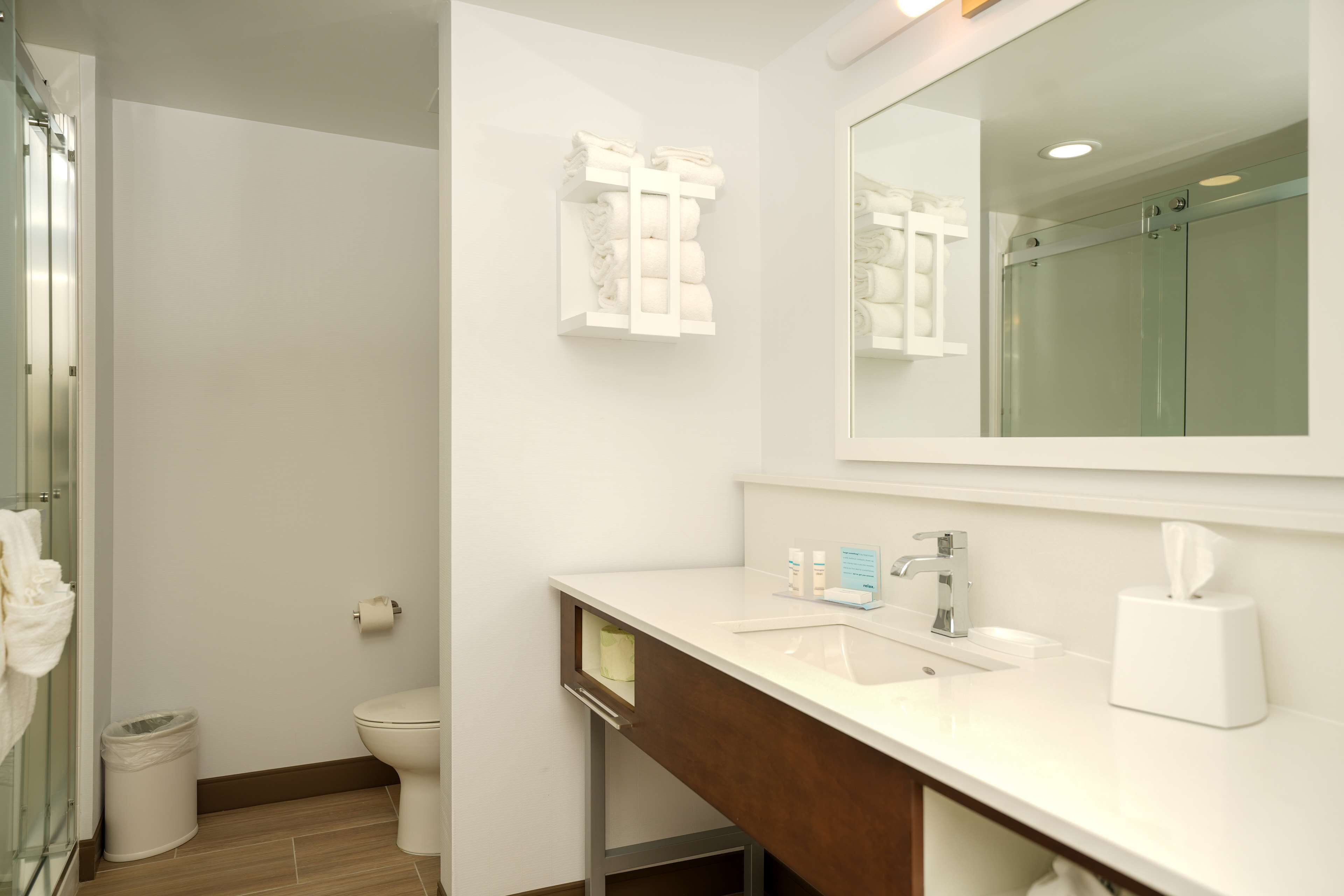 Uma casa de banho moderna com lavatório branco, espelho e porta-toalhas.