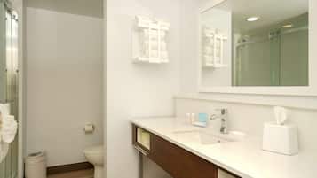 Uma casa de banho moderna com lavatório branco, espelho e porta-toalhas.