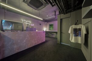 Uma área de recepção moderna com balcão de mármore, uma televisão e um letreiro com a inscrição '9oyo3'.