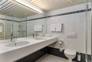 Um banheiro moderno com duas pias, vaso sanitário e chuveiro.