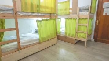 Quarto de dormitório com beliches, piso de madeira e uma porta com aviso.