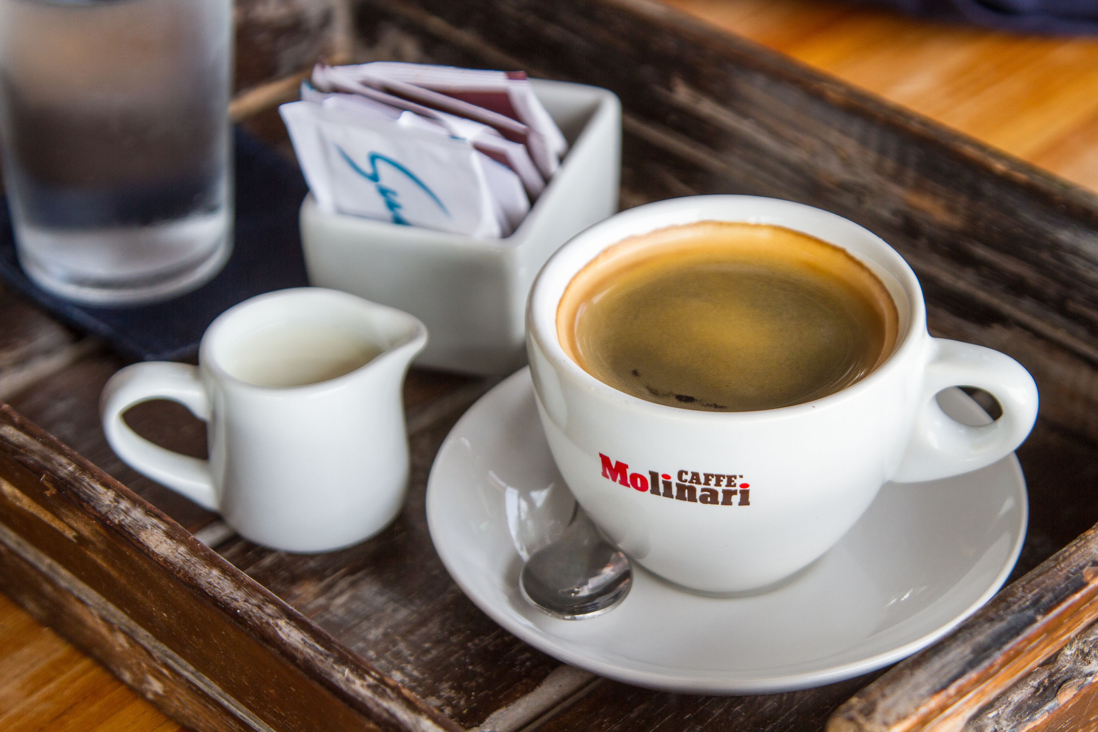 Uma bandeja com uma xícara de café, um jarro pequeno e um copo de água.