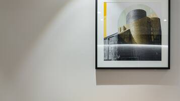 Um interior moderno com uma obra de arte emoldurada na parede, um armário de madeira e uma poltrona de couro marrom.