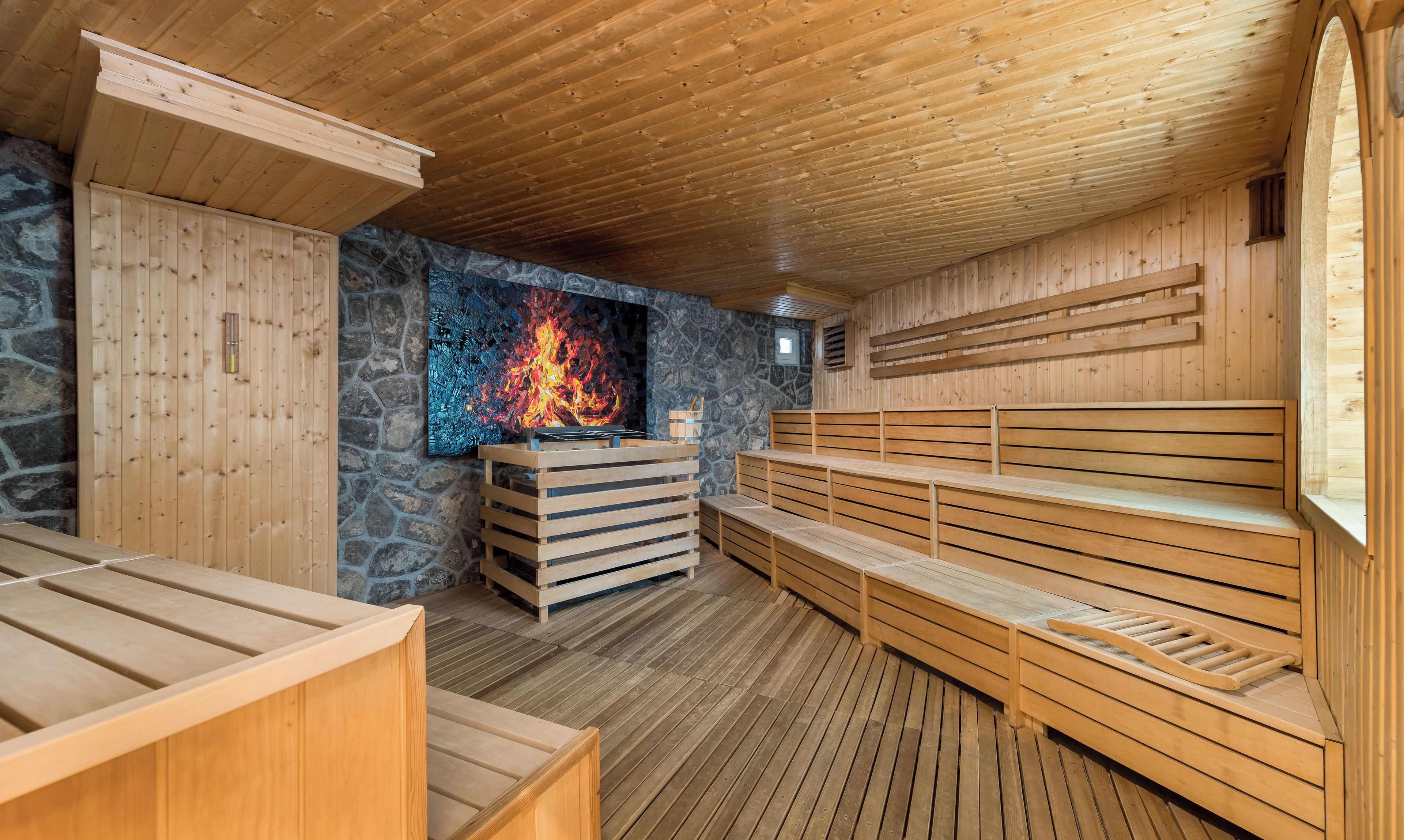 Uma sauna com bancos de madeira e parede de pedra.