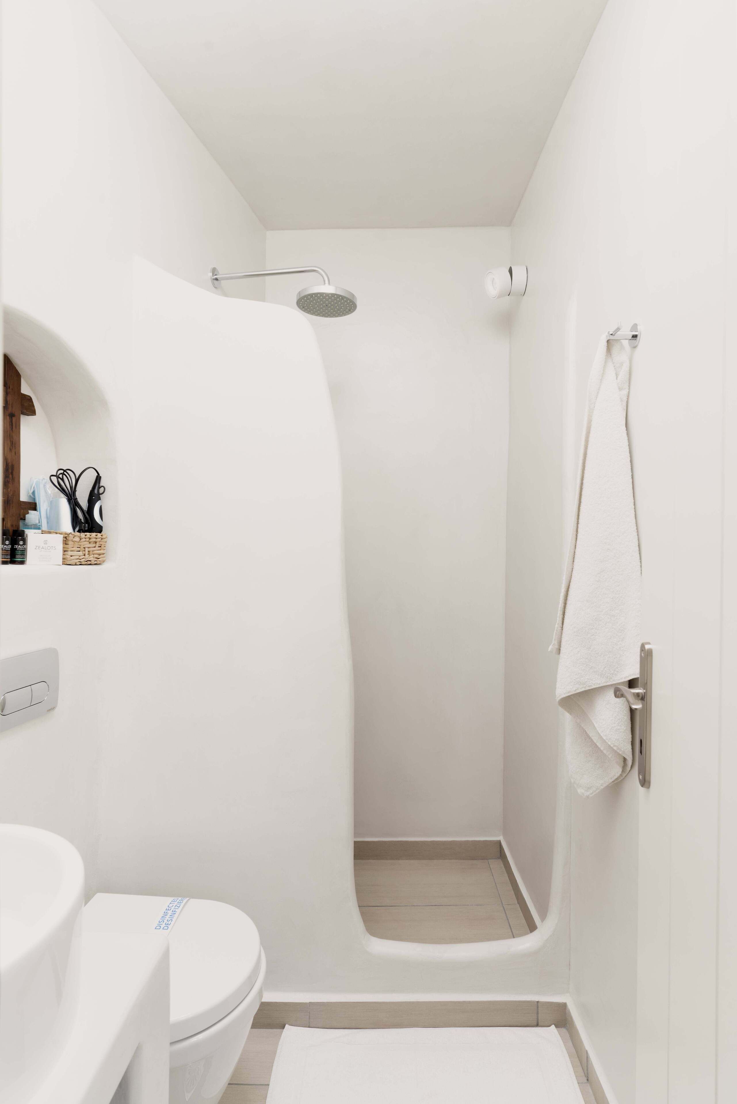Casa de banho compacta com chuveiro, sanita e porta-toalhas.