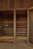 Uma sauna de madeira com vários bancos e um banco com toalha.