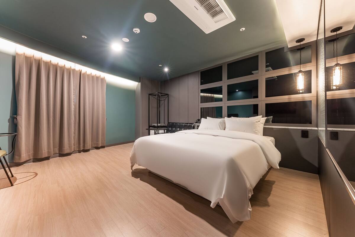 Quarto de hotel moderno com uma cama grande, uma escrivaninha e uma cadeira.