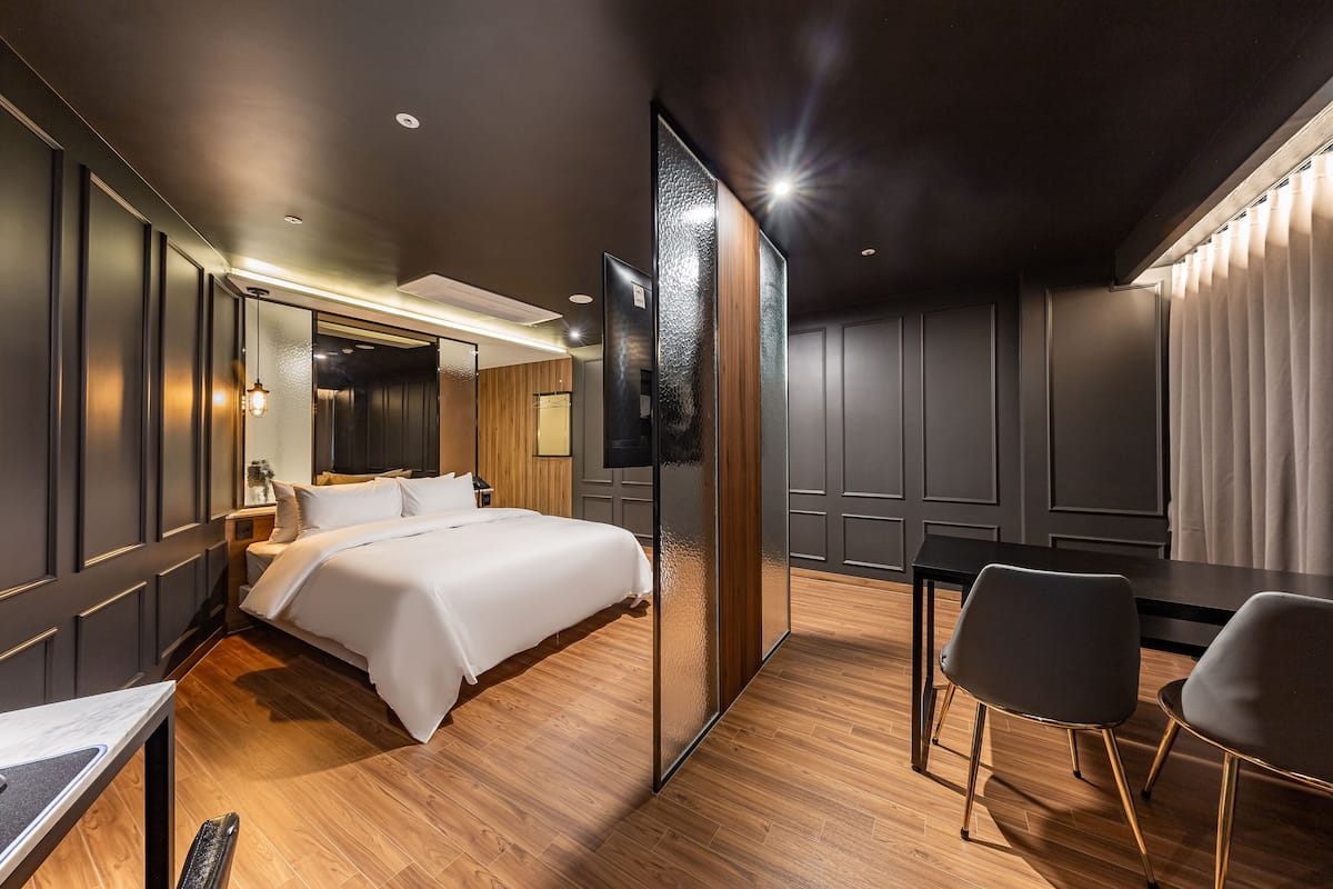 Quarto de hotel moderno com uma cama grande, uma escrivaninha e uma cadeira.