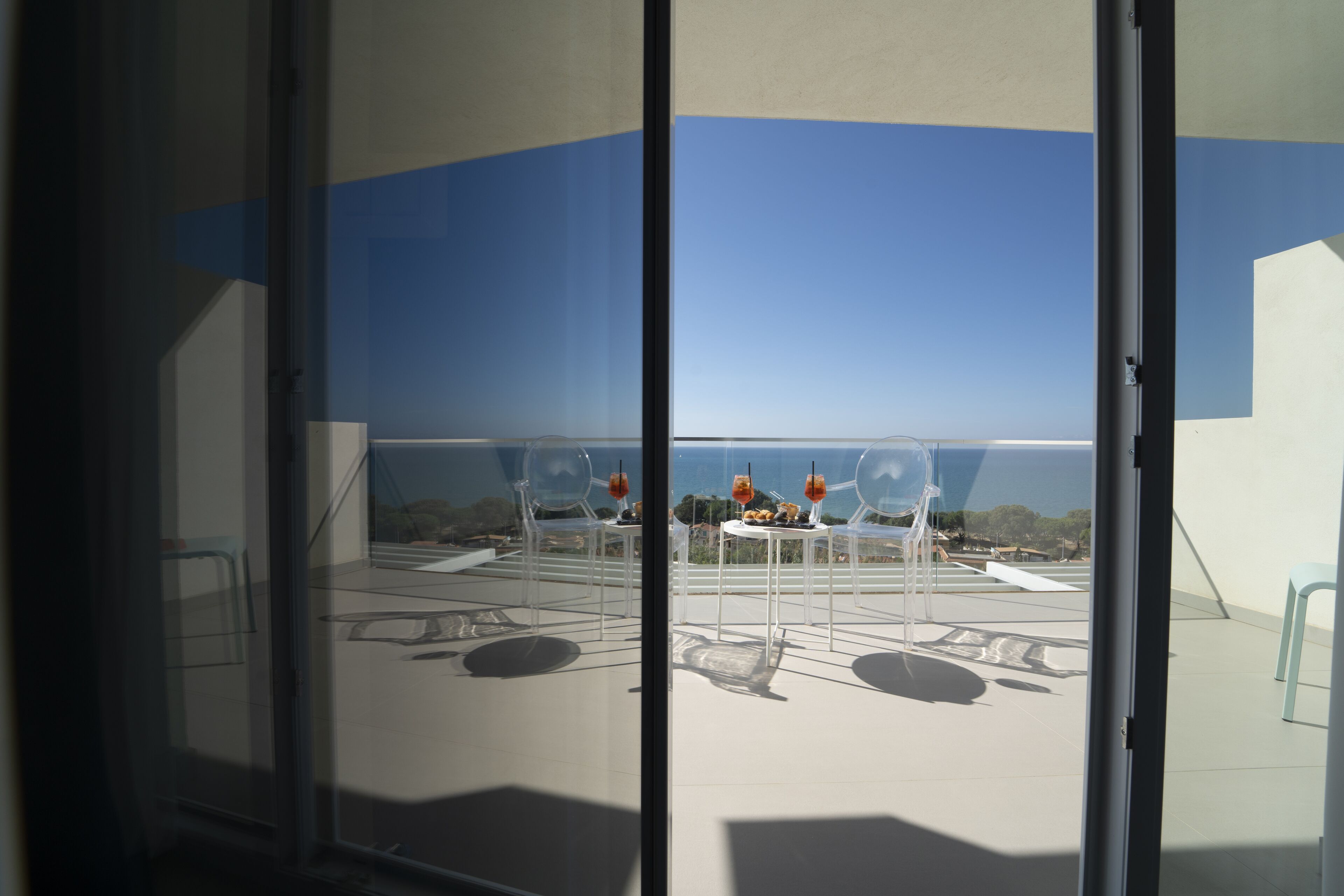 Varanda com portas de vidro transparente, com vista para o céu e paisagem distante.