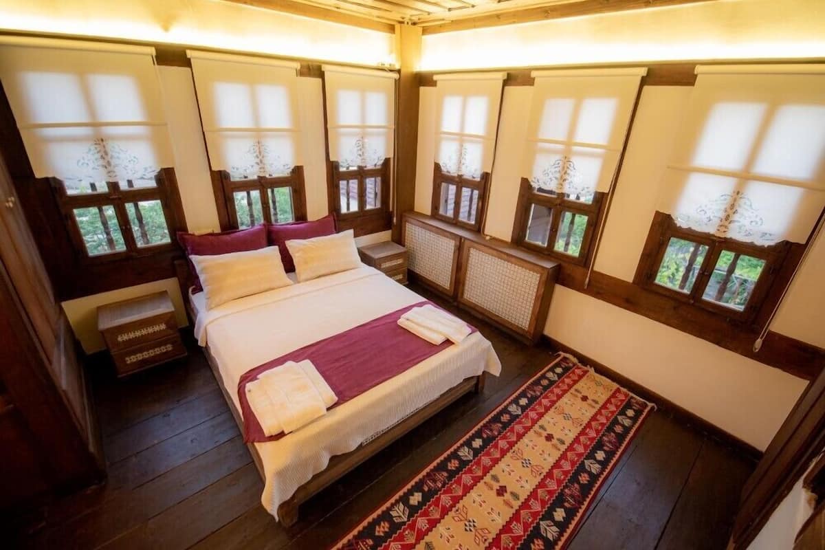 Um quarto de madeira tradicional com uma cama, um criado-mudo e uma janela com vista.