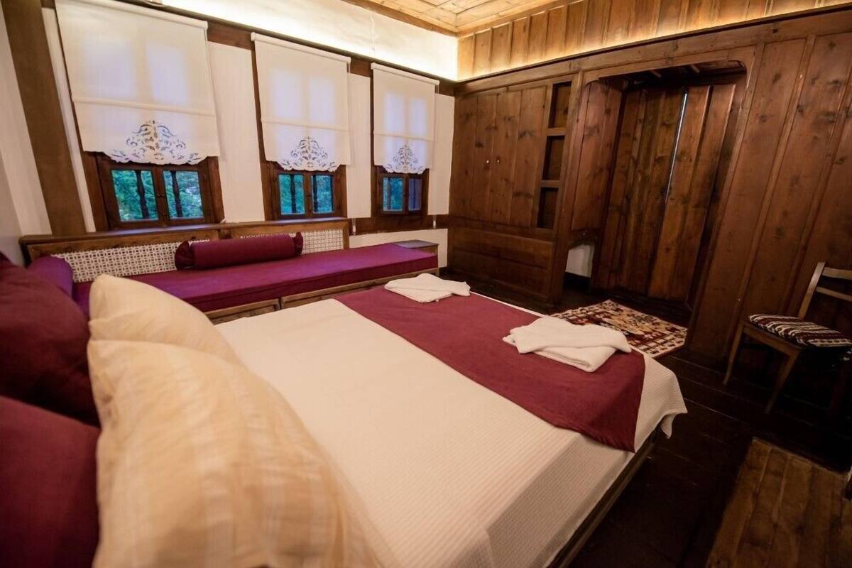 Um quarto com cama, um banco e um guarda-roupa.