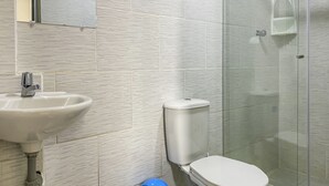 Casa de banho com lavatório, sanita e cabine de duche em vidro.