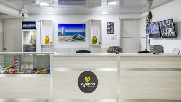 Uma área de recepção de hotel com design moderno, incluindo um balcão de atendimento, um refrigerador e uma grande janela com vista panorâmica.