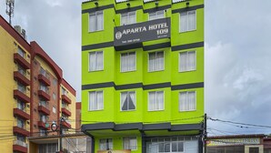 Um edifício de vários andares com fachada verde vibrante, várias janelas e sacadas.