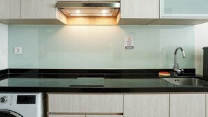 Uma cozinha moderna com bancada preta, pia de aço inoxidável e armários de madeira.
